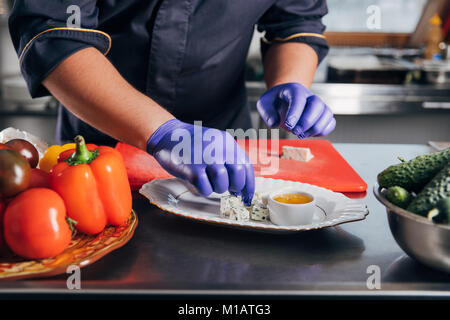 cropped shot of chef putting cheese pieces onto pizza at restaurant ...
