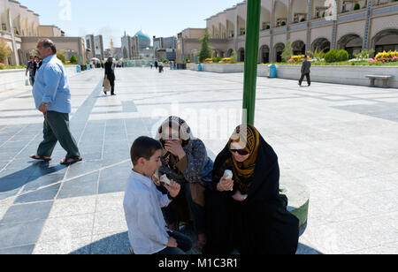 Iranian people walk by the streets of Mashhad near the Imam Reza shrine ...