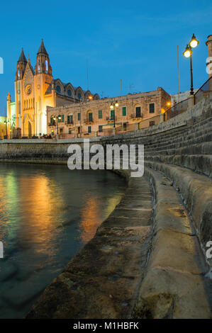 Illuminated Balluta parish church in Balluta bay, Malta wide panorama ...