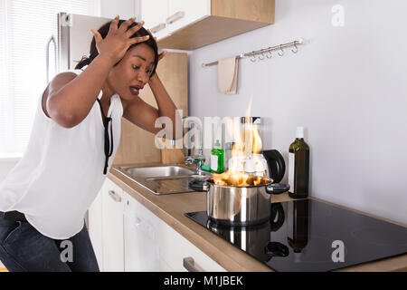 Frustrated Woman Looking At Utensil On Fire Stock Photo - Alamy