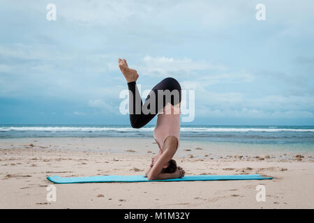 Young woman practice balance asanas on Summer yoga session on beach ...