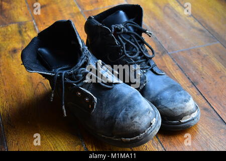 An old worn out black leather shoe boot with moss grass growing on in ...