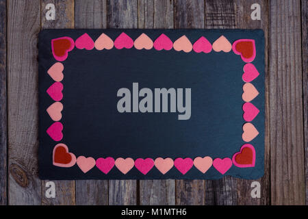 Slate stone board with colorful hearts on vintage wooden background ...