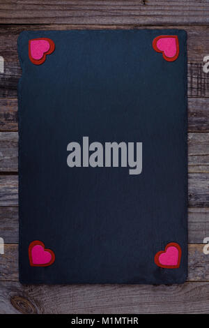 Slate stone board with colorful hearts on vintage wooden background ...