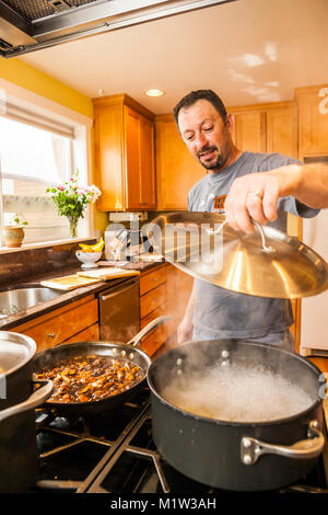 Chef lifting lid on pan of spaghetti on stove, elevated view Stock ...