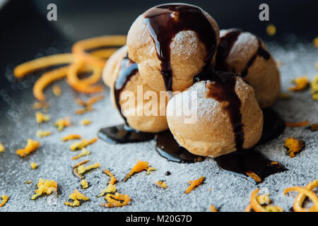 Profiterole dessert with white chocolate and dark chocolate syrup on a ...