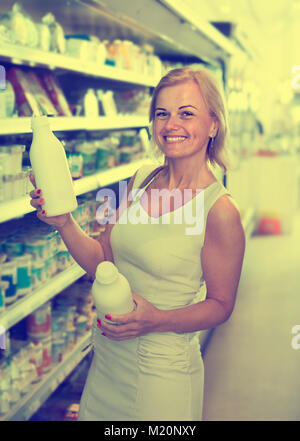 Customer selecting groceries from refrigerated shelves in a supermarket ...