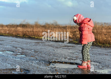 Girl looking at her reflection in a puddle of water in the street Stock ...