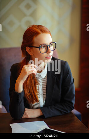 Young redhead woman working as manager at retail boutique praying with hands together asking for ...