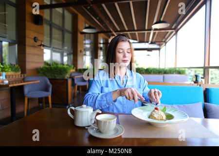 Attractive girl drinking tea with cake in cafe Stock Photo - Alamy