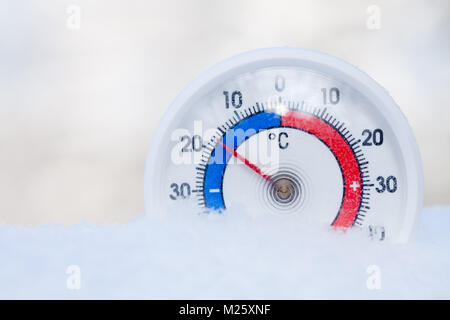 Thermometer with celsius scale placed in a fresh snow showing sub-zero ...