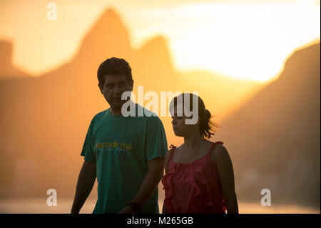 Couple walking along Ipanema beach at night,with twin peaks of Two ...