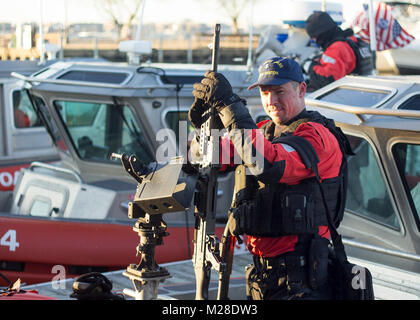 A Coast Guard member equips cold weather gear and weapons before ...