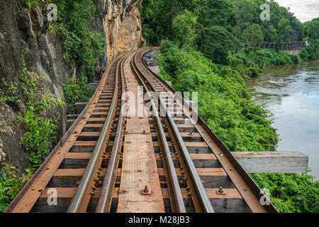Old railroad tracks on bridge beside cliff rock, focus on railroad ...