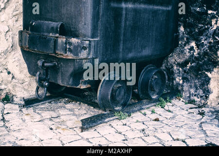 A cart carrying coal on a rail track beside the entrance of a coal mine ...