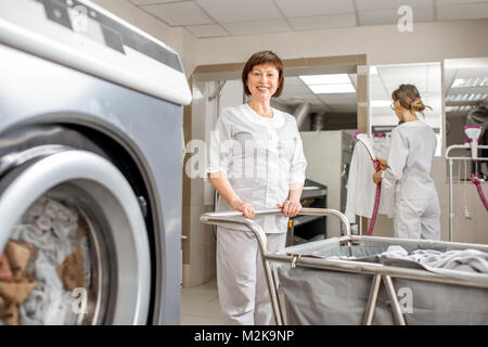 people, profession, woman working as laundress in the laundrette ...