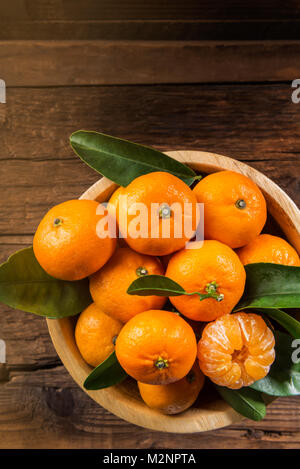Delicious and beautiful mini Tangerines with leaves in the wooden bowl ...
