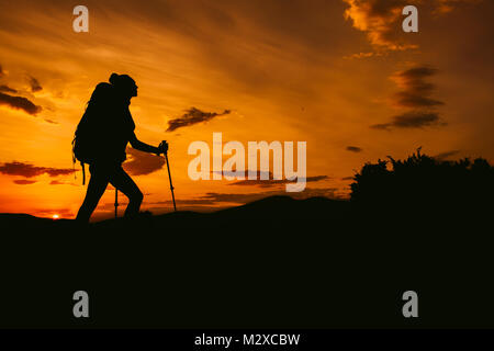 Silhouette hiker woman tracking with backpack and trekking pole, sunset ...