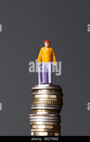 Pension concept. Old person figure on a stack of coins Stock Photo - Alamy