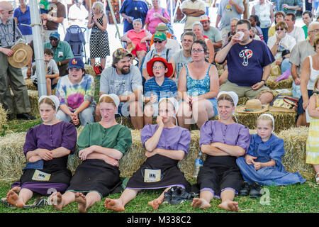 A young barefoot Amish girl in a green and black outfit isolated on a ...