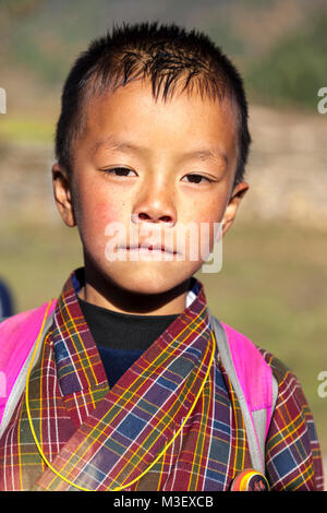 Portrait of a young Bhutanese boy wearing a traditional striped gho ...