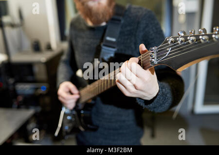 A skilled man playing an electric guitar in a recording studio as part ...