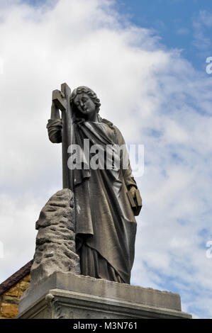 Statue Looking Down Upon a Grave with a Cloudy Blue Sky Background ...
