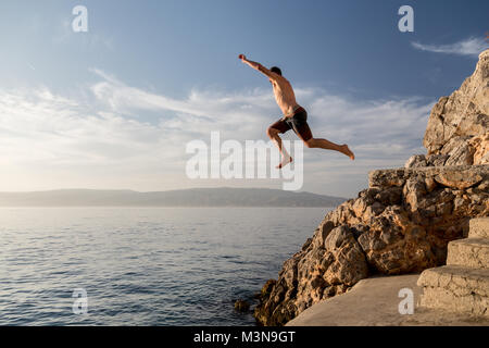 Excited young man jumping from happiness, smiling amazed and holding ...