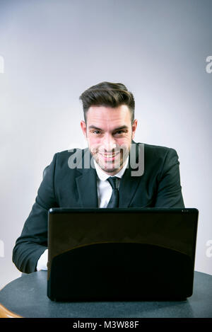 Attractive happy smart young man sitting on a floor in the living room ...