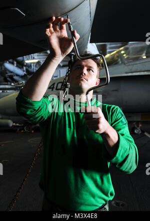 Electronics Technician 3rd Class installs a safety harness after ...