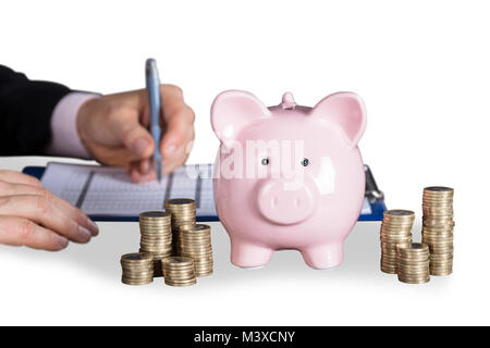 A stack of paper money and coins near a calculator on a white surface ...