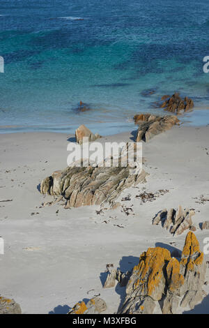 White sandy beach with outcrops of lichen covered rocks on Carcass ...