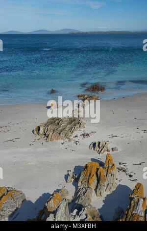 Jagged lichen-covered rocks in the foreground give way to rolling green ...