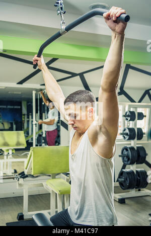 Muscular bodybuilder using lat pulldown machine in gym Stock Photo - Alamy