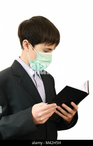 boy in medical mask reading book in classroom near african american ...