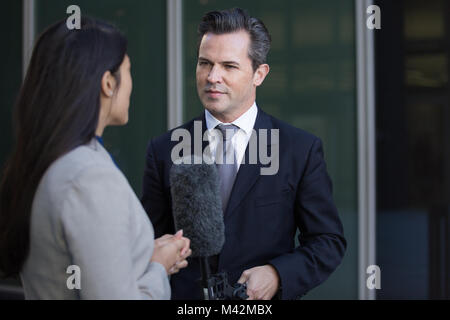 Man being interviewed on the street by BBC television news reporter and ...