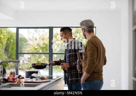 Male friends having a beer whilst cooking a meal Stock Photo - Alamy