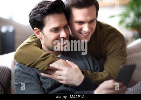 Young latin couple using smartphone sitting on the sofa at home Stock ...
