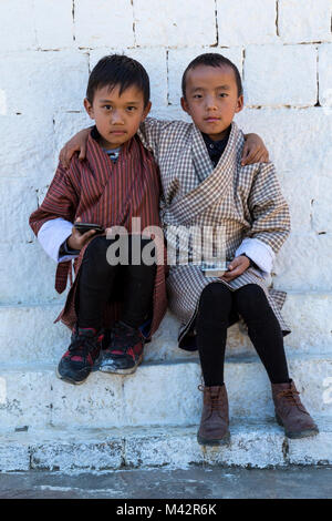 Young Bhutanese boys wearing traditional striped gho (robe) in Nimshong ...