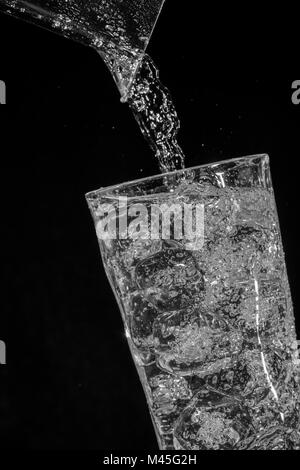 sparkling water overflow over ice cubes Stock Photo - Alamy
