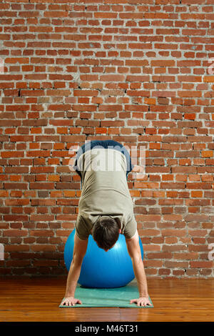 Athletic man doing exercises for the balance on rubber ball with ...