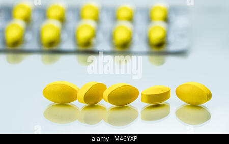Macro shot of yellow oval tablet pills on white background and purple ...