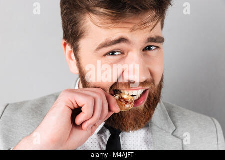 Portrait of a man biting a gold coin Stock Photo - Alamy