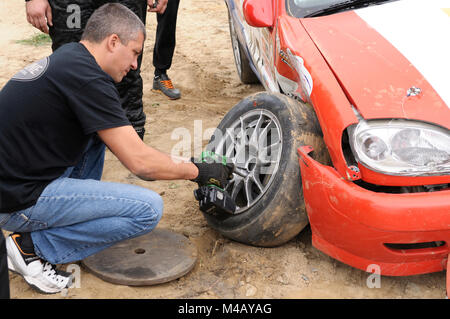 Mechanics replacing wheel of a damaged racing car at a pit lane after ...