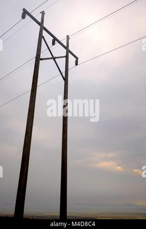 Wooden H-frame transmission line power poles are pictured at sunset ...