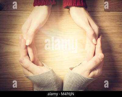 Woman and man making circle with hands. Warm light inside, concept of ...
