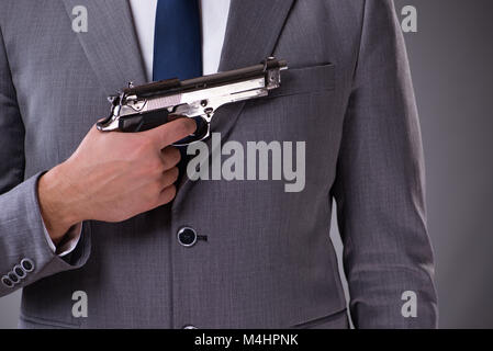 Businessman pulling the gun out of pocket Stock Photo - Alamy