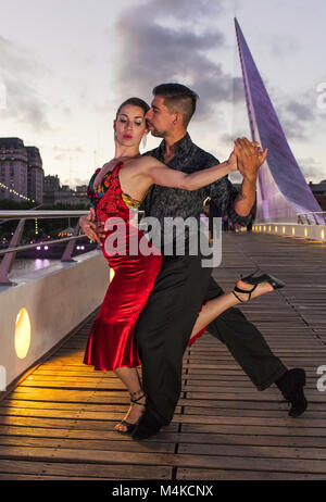 A couple dancing tango on the "Puente de la Mujer" at twilight. Puerto ...