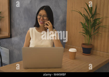 Pregnant businesswoman talking by mobile phone at desk in office Stock ...