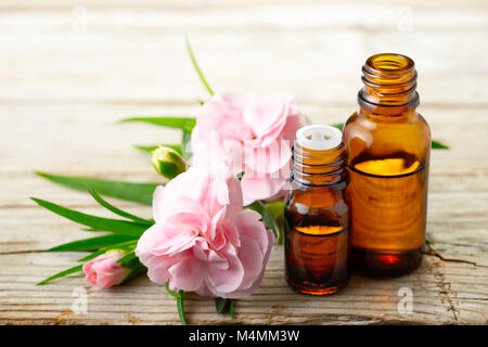 Carnation absolute essential oil and pink flowers on the wooden board ...